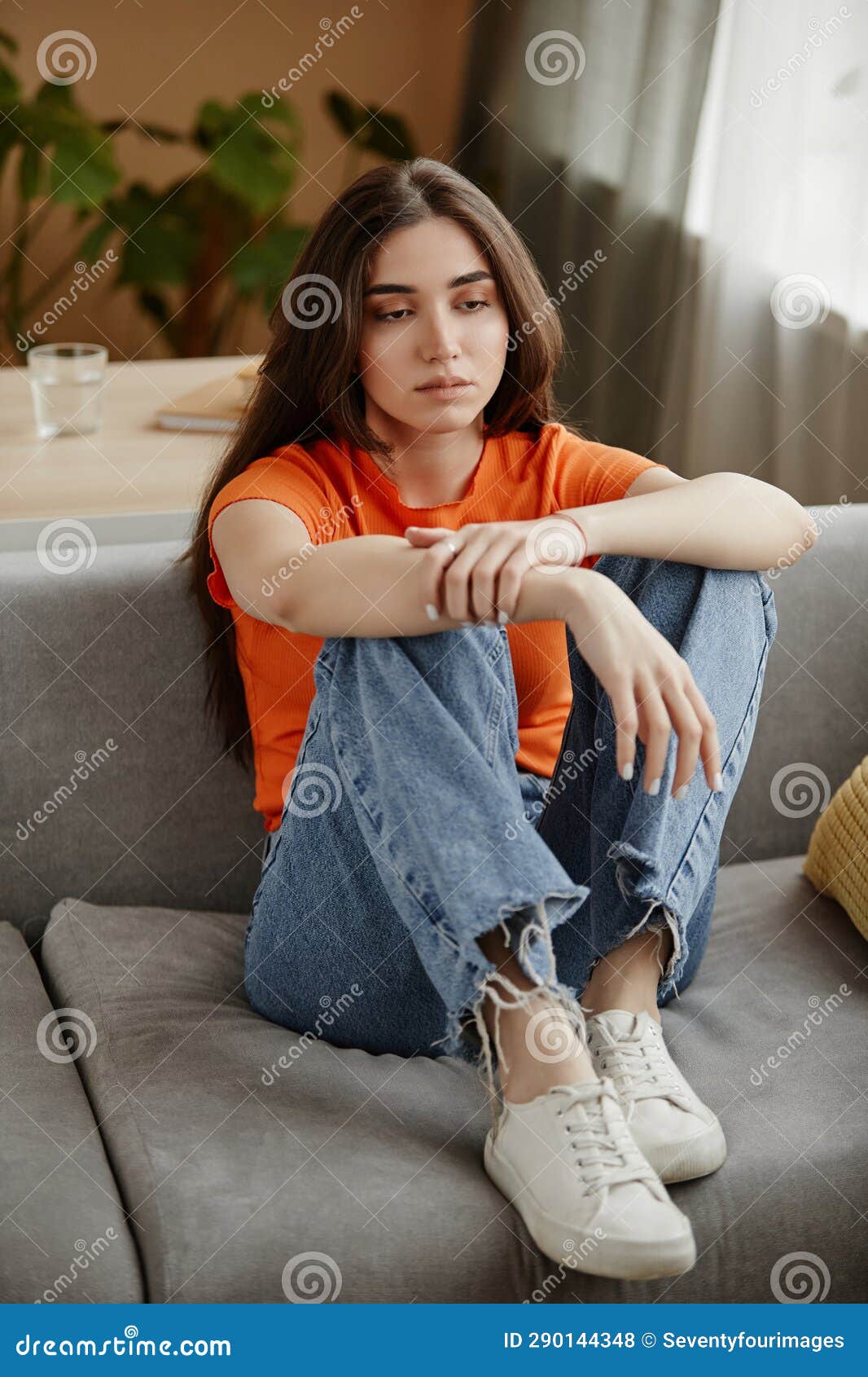 Depressed Young Woman Sitting On Couch Alone Staring Blankly Stock