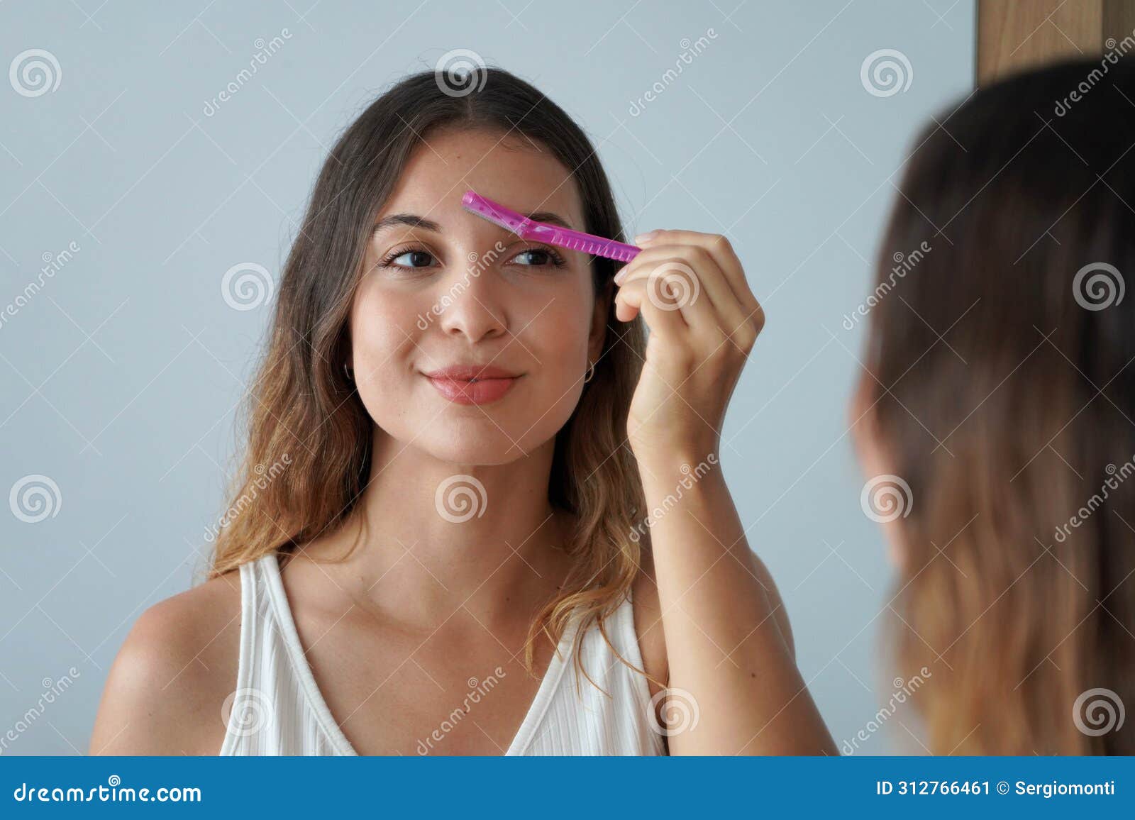 Dermaplaning Pretty Hispanic Girl Shaving Her Eyebrows By Razor On The Mirror At Home Stock