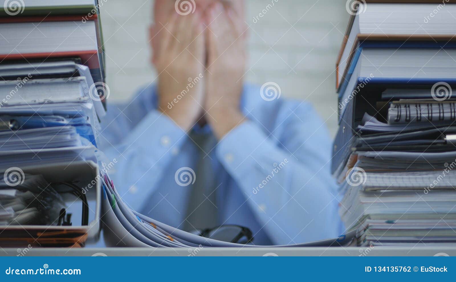 Desperate And Worried Manager Keeping His Head In Hands In Blurred