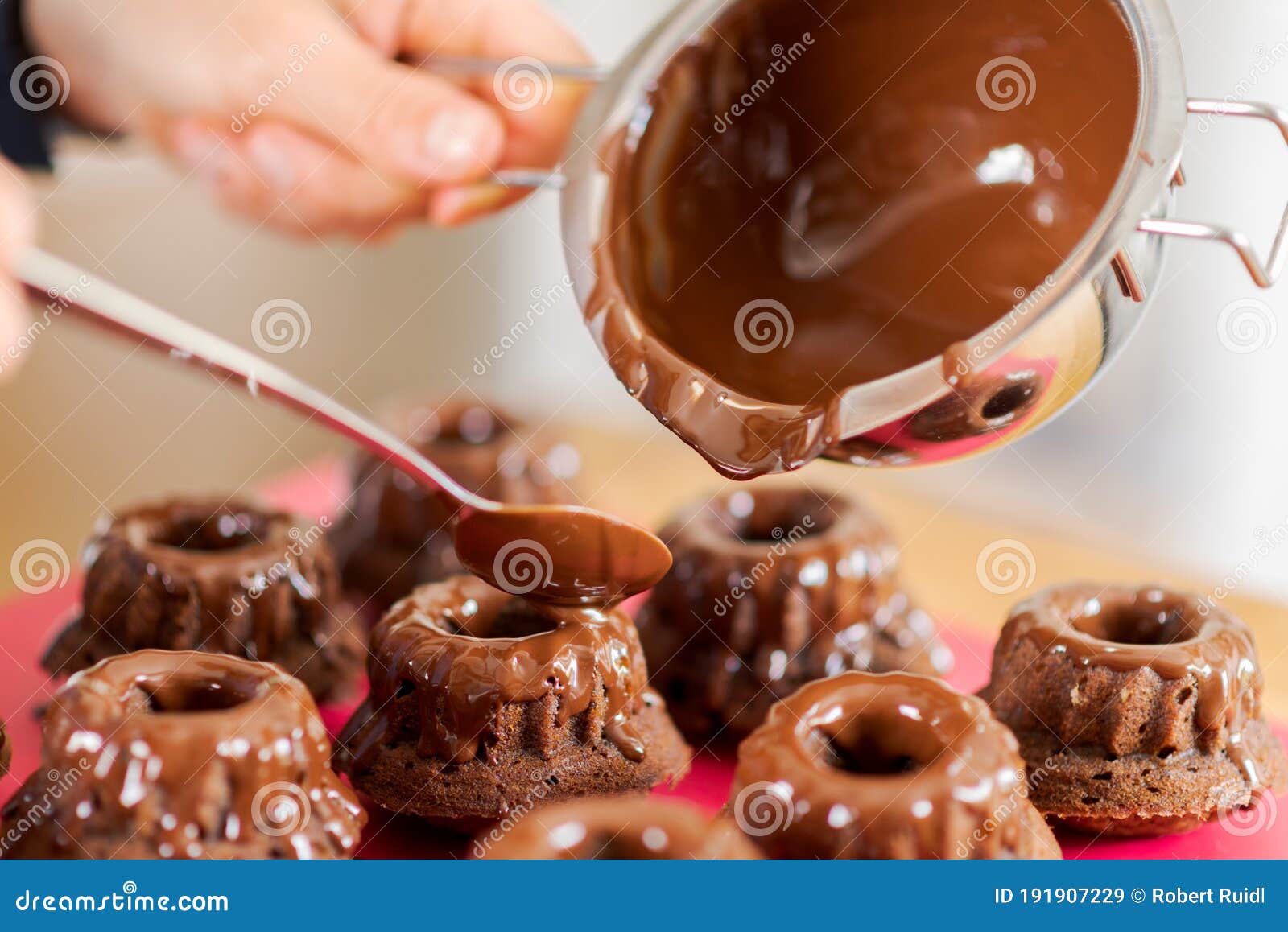 Detail of Chocolate Icing Being Applied on Top of Mini Ring Cakes on ...