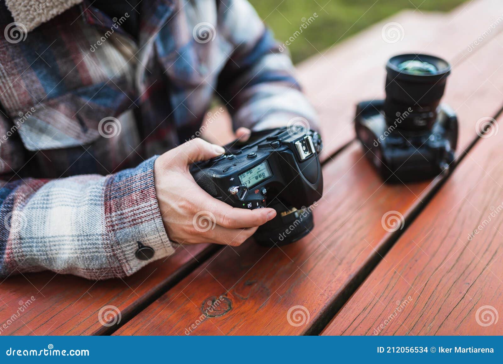 Detail of the Hands of a Man Touching a Camera Sitting at a Table with ...