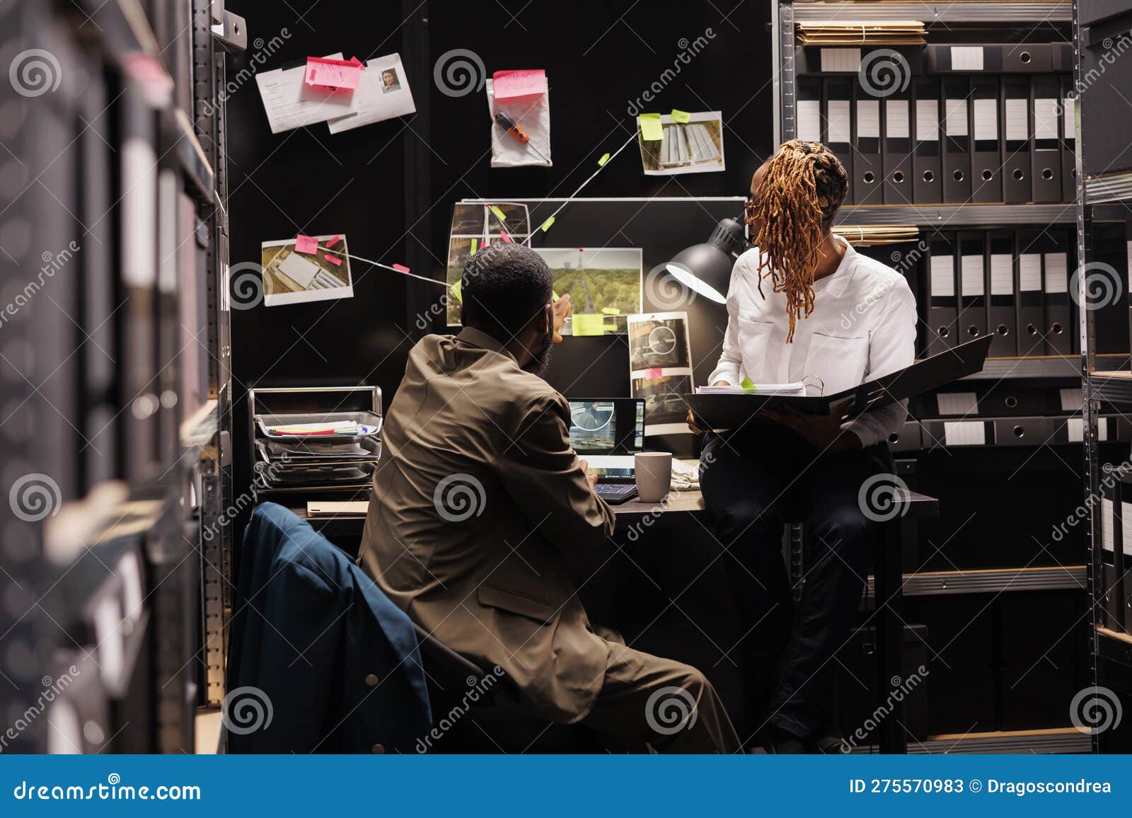 Detective Partners Analyzing Surveillance Photos Hanging On Evidence