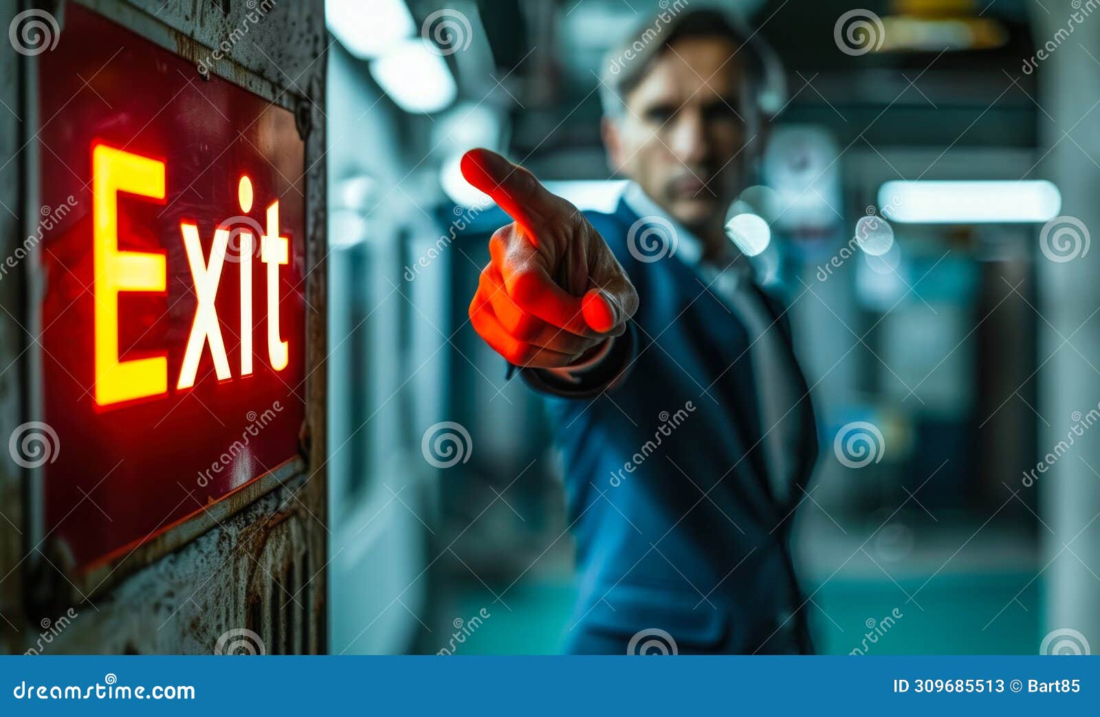 Determined Businessman Pointing Towards an Exit Sign in a Corridor ...