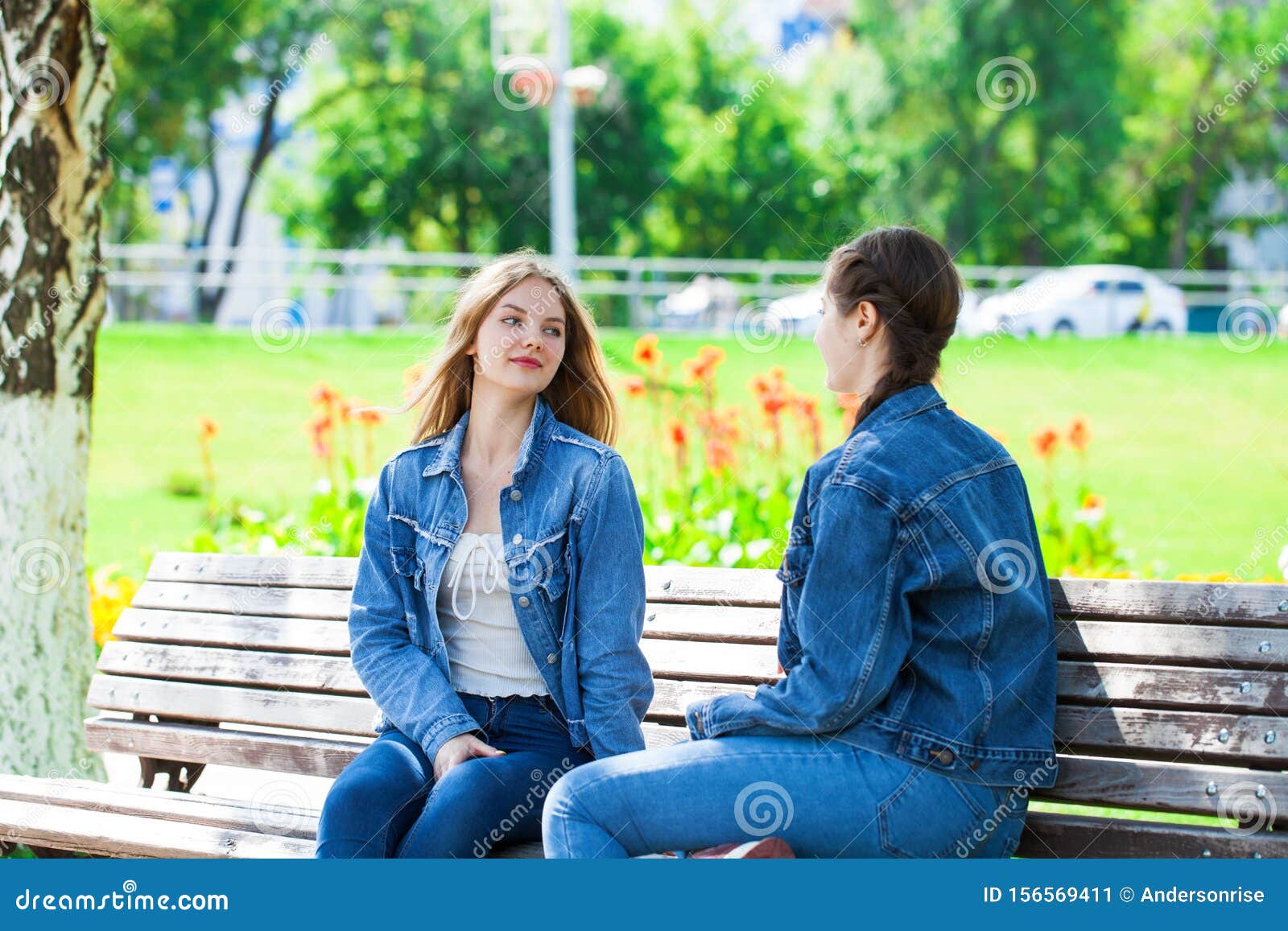 Deux Belles Copines Parlent Dans Un Parc Assis Sur Un Banc Image Stock
