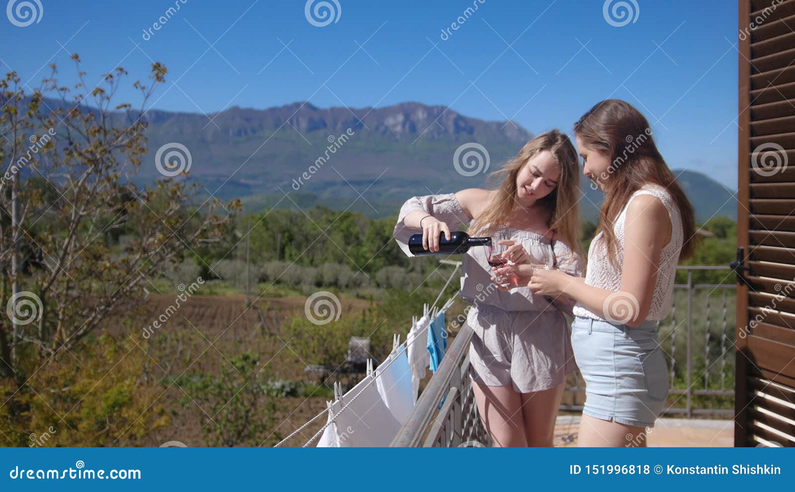 Deux Jeunes Femmes De Sourire Versant Le Vin Sur Le Balcon Photo stock ... Deux Jeunes Femmes De Sourire Versant Le Vin Sur Le Balcon Photo stock ...