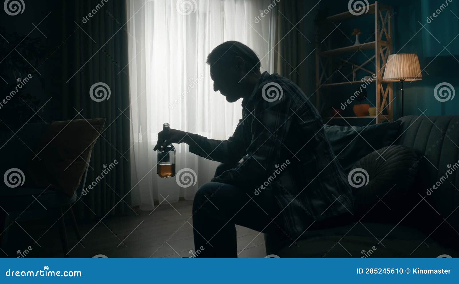 A Devastated Man Sits in a Dark Room with a Bottle of Alcohol. Side ...