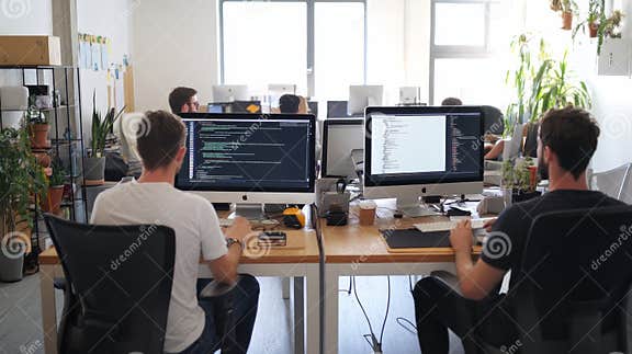 Developers Working on Code Together in a Busy Office Environment with Multiple Screens. Team ...