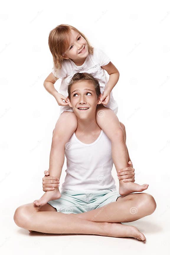Die Schwester Sitzt Auf Ihrem Bruder `s Nacken Und Zieht Seine Hände An Den Ohren Jeder Lacht