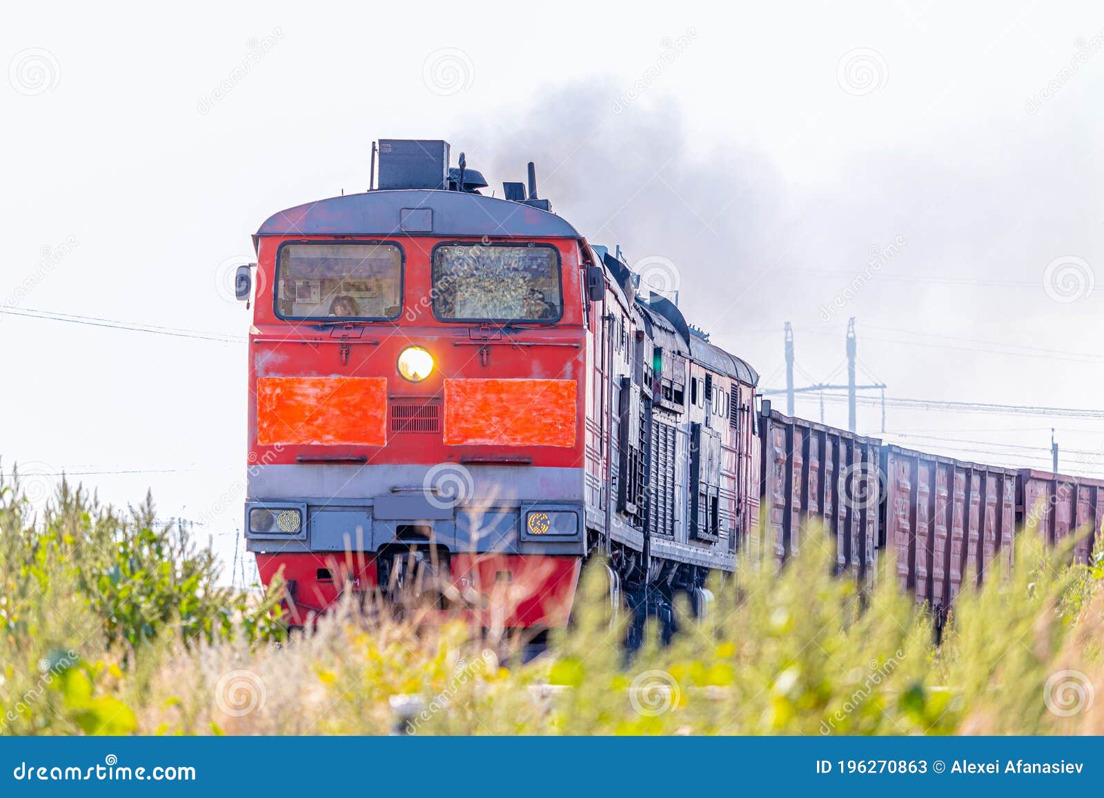 A Diesel Locomotive Pulls a Train of Freight Cars Across the Fields ...