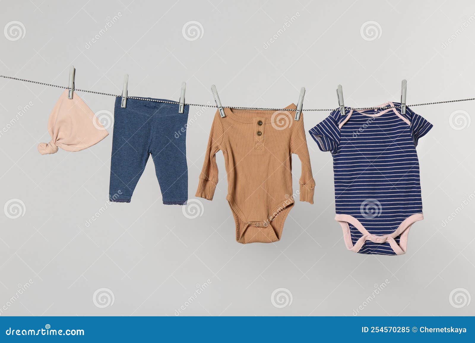 Different Baby Clothes Drying on Laundry Line Against Light Background ...