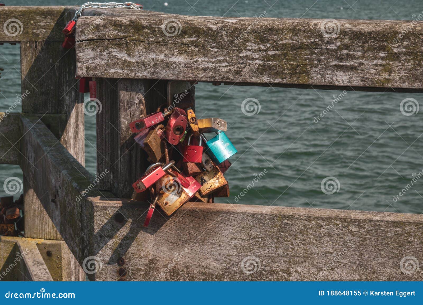 Many Different Coloured Padlocks Hang As a Bundle on a Wooden Railing ...