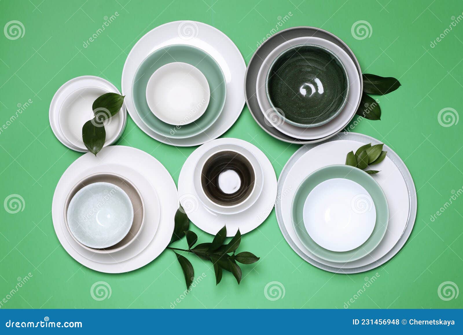 Different Dishware and Leaves on Green Background, Flat Lay Stock Photo ...