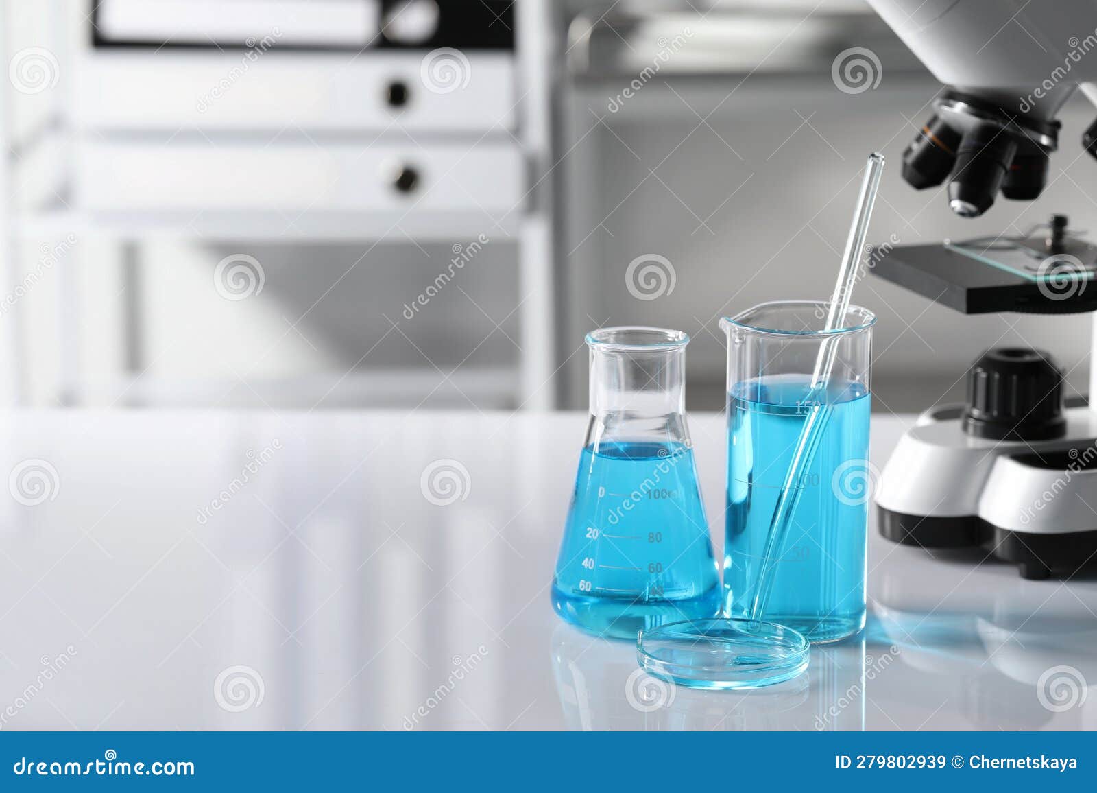 Different Laboratory Glassware with Light Blue Liquid Near Microscope ...
