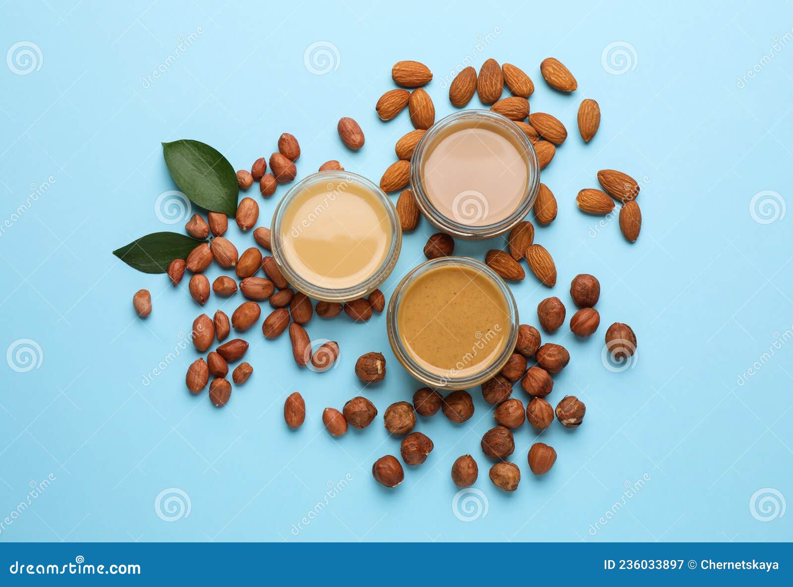 Different Types Of Delicious Nut Butters And Ingredients On Light Blue Background Flat Lay