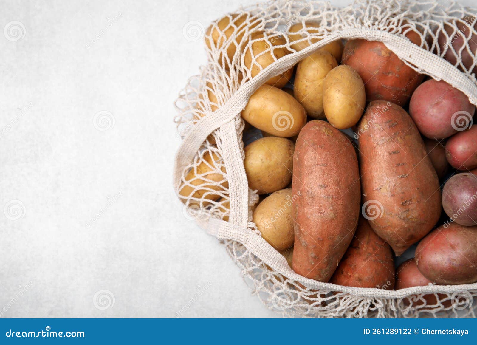 Different Types of Fresh Potatoes in Net Bag on White Table, Top View ...
