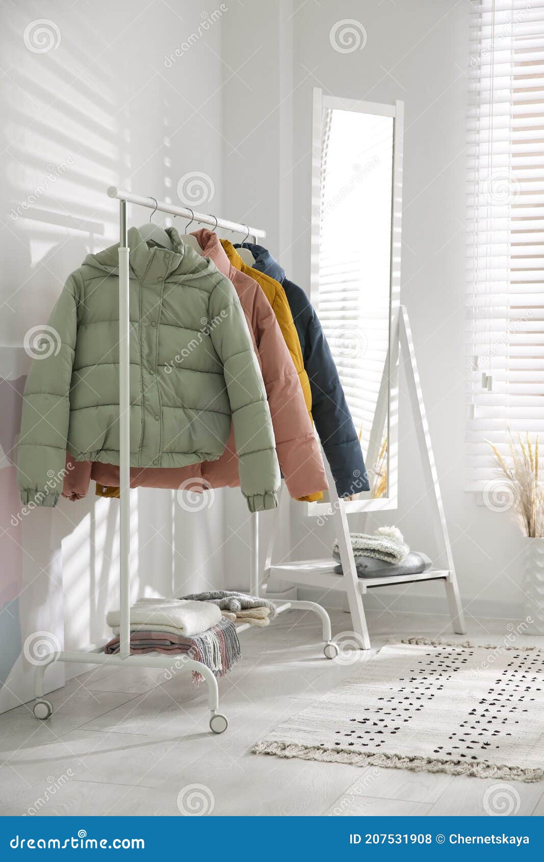 Different Warm Jackets on Rack in Stylish Room Interior Stock Photo ...