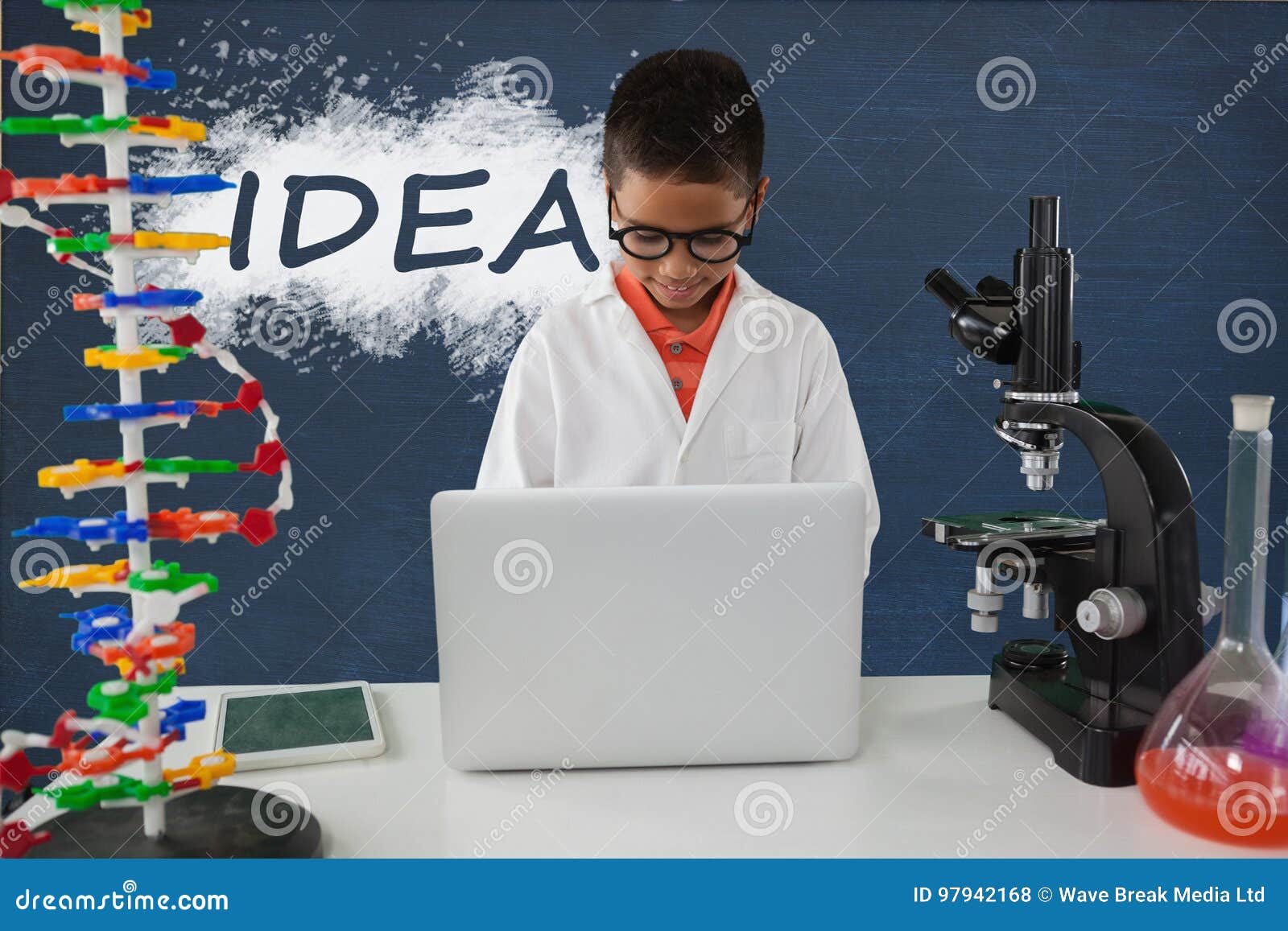 Student Boy at Table Using a Computer Against Blue Blackboard with Idea ...