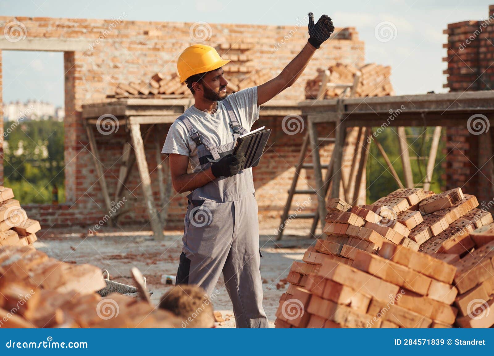 Showing and Holding Little Shovel and Brick. Handsome Indian Man is on ...