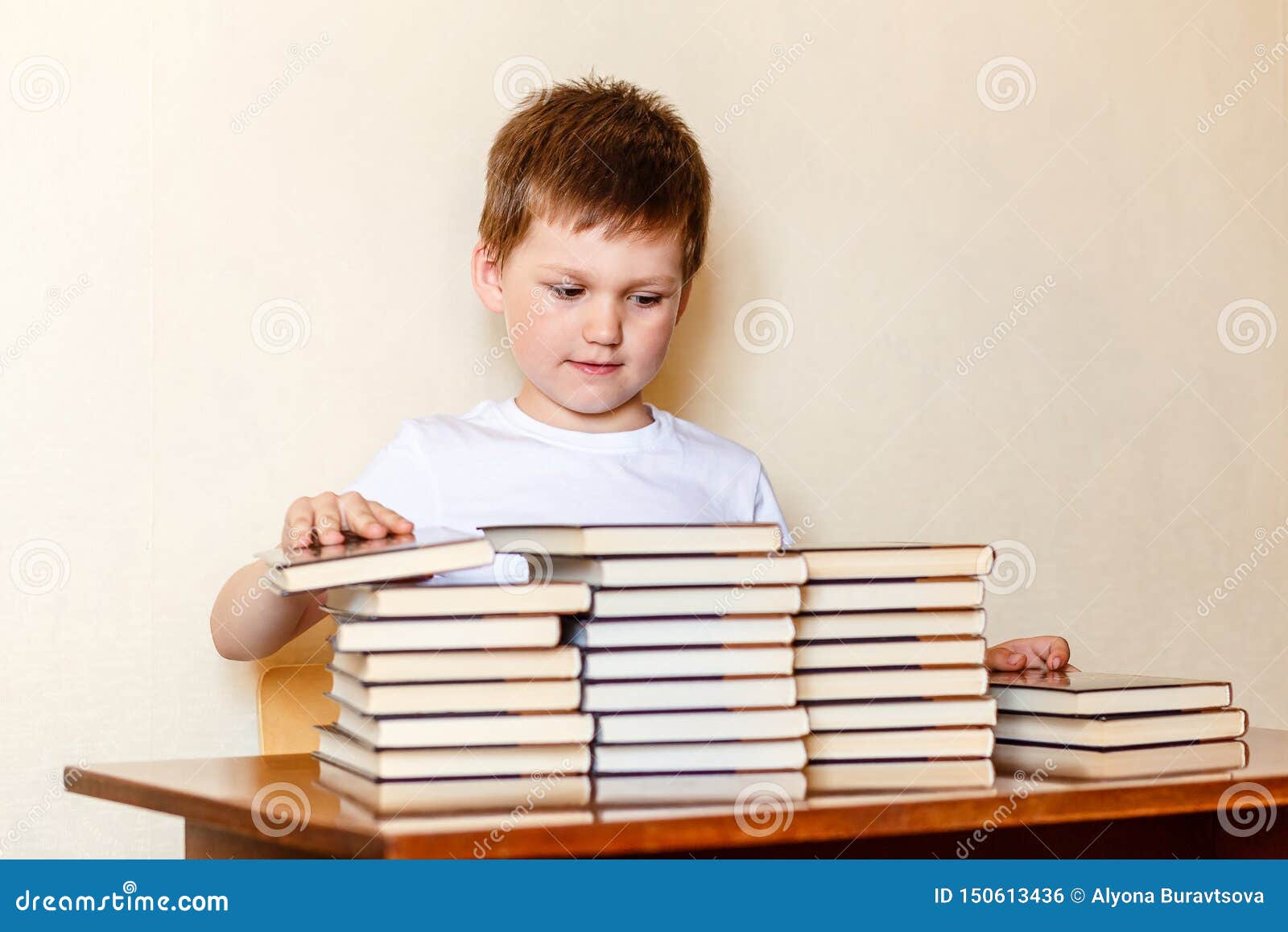 A Diligent Boy Sits at a Desk and Puts Books on Stacks Stock Photo ...