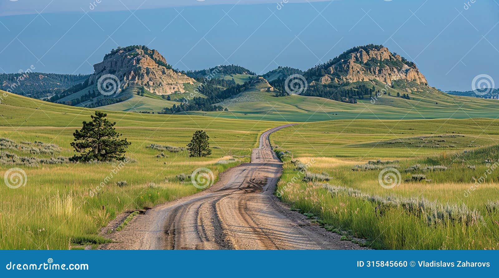 A Dirt Road Winds through a Grassy Plain with Two Mountains in the ...