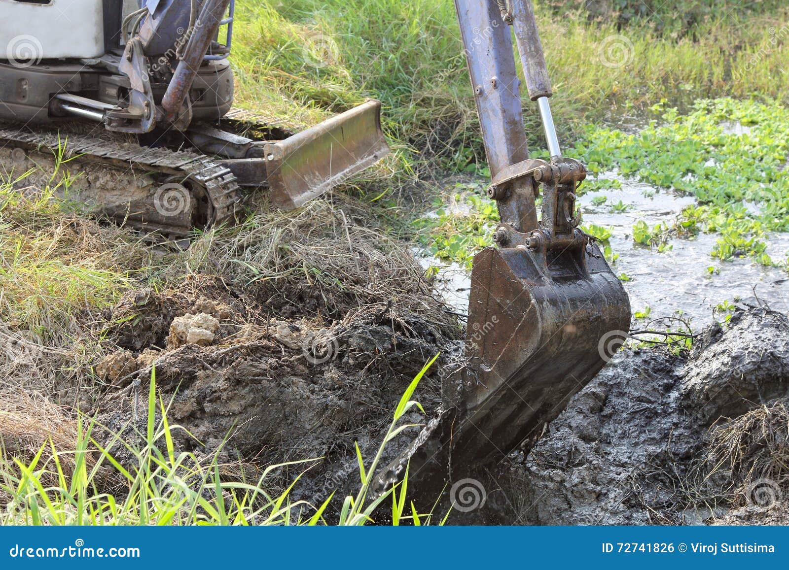 Dirty Bucket of Backhoe Digging Mud and Weed in a Canal. Stock Photo ...