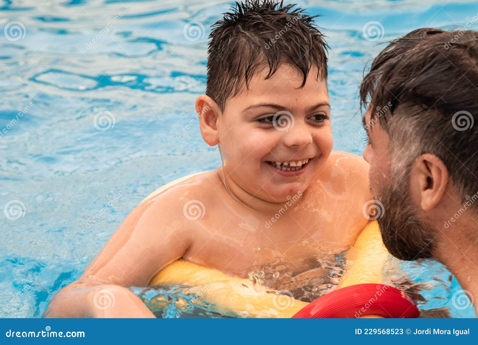 Disabled Boy with a Float Laughs As he Plays and Swims in a Pool with ...