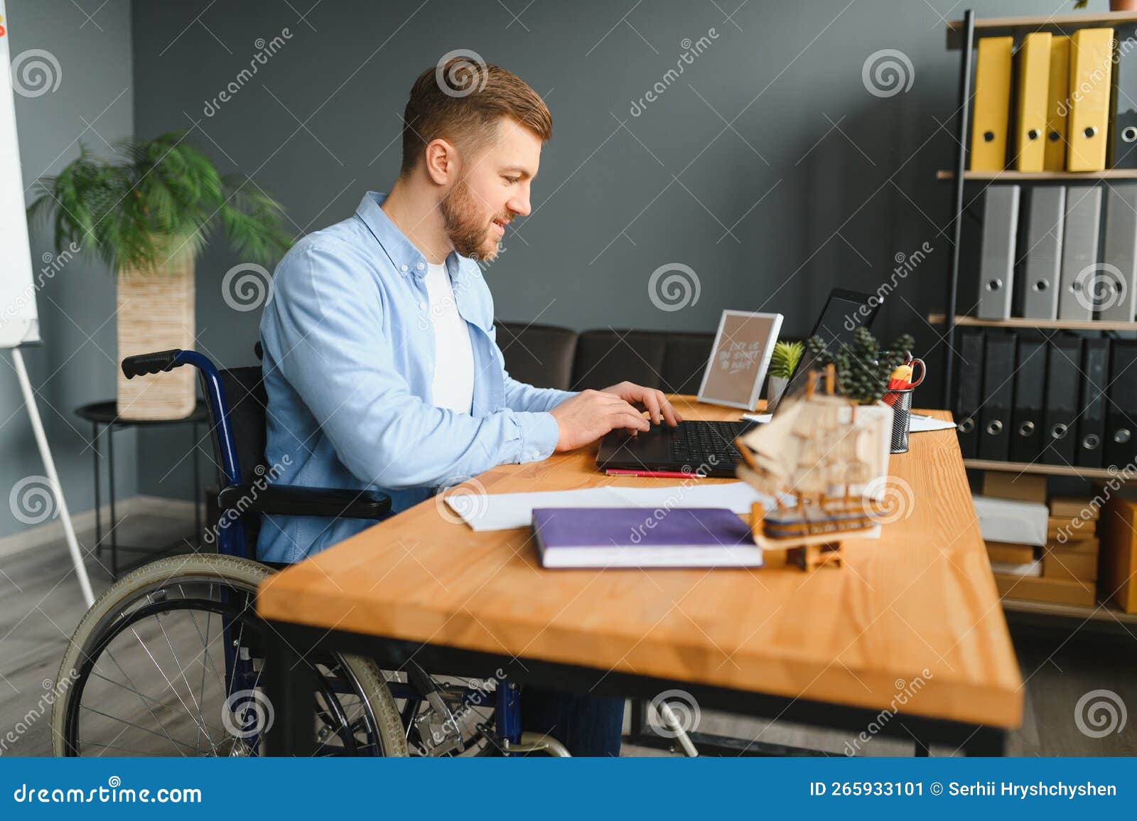 Disabled Person in the Wheelchair Works in the Office at the Computer ...