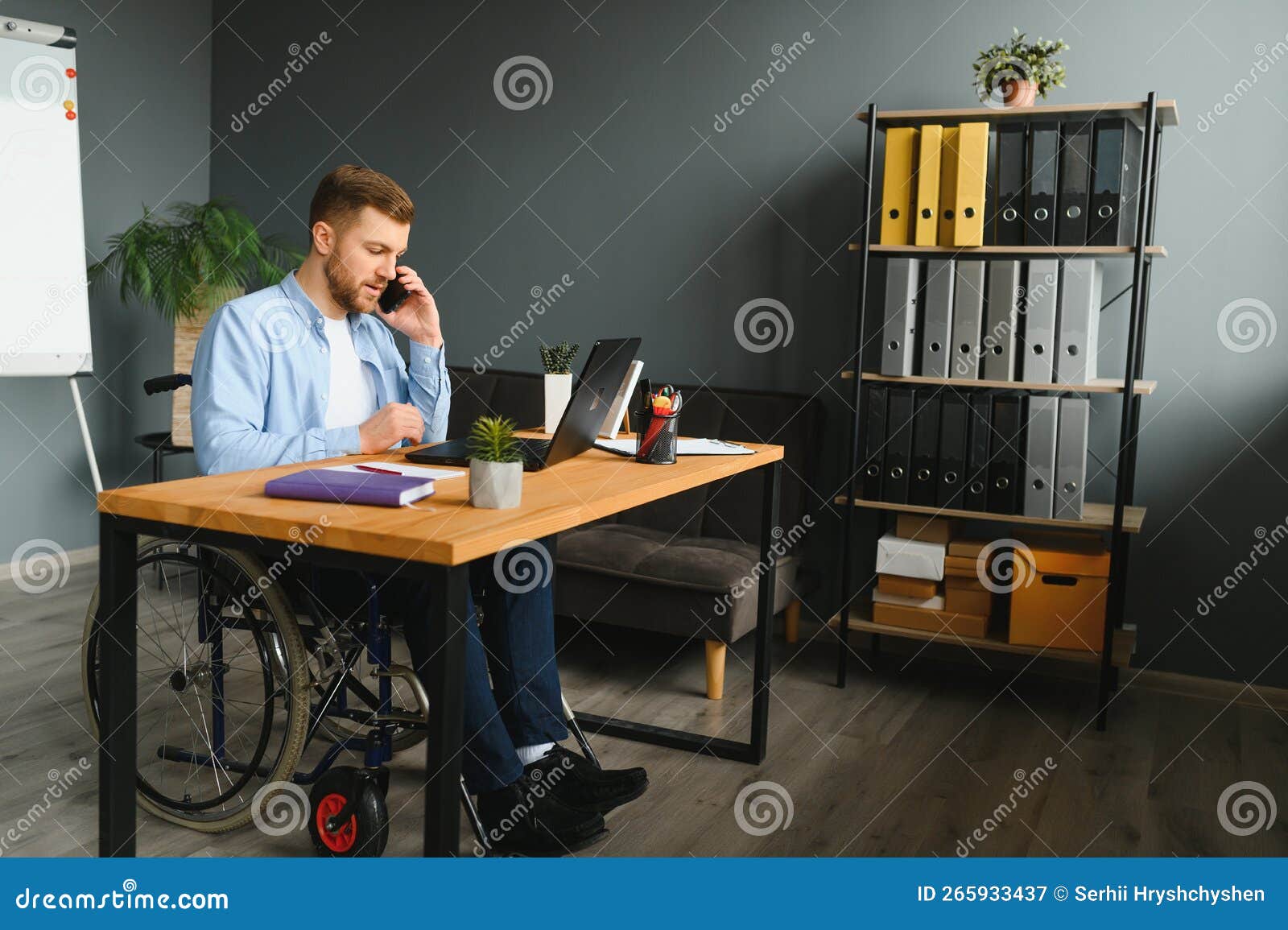 Disabled Person in the Wheelchair Works in the Office at the Computer ...