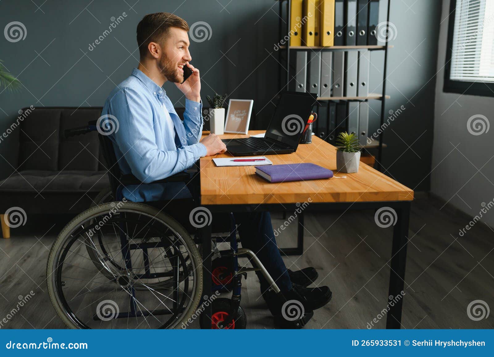 Disabled Person in the Wheelchair Works in the Office at the Computer ...