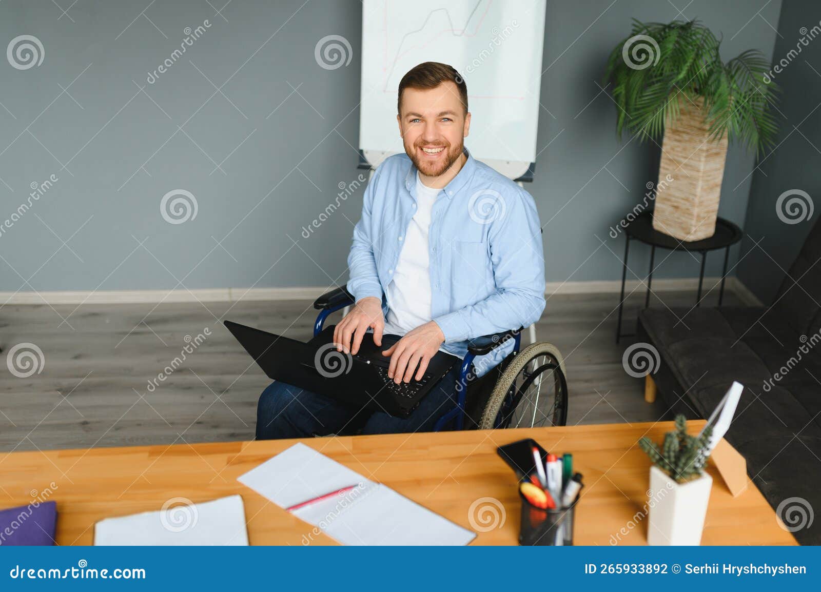 Disabled Person in the Wheelchair Works in the Office at the Computer ...