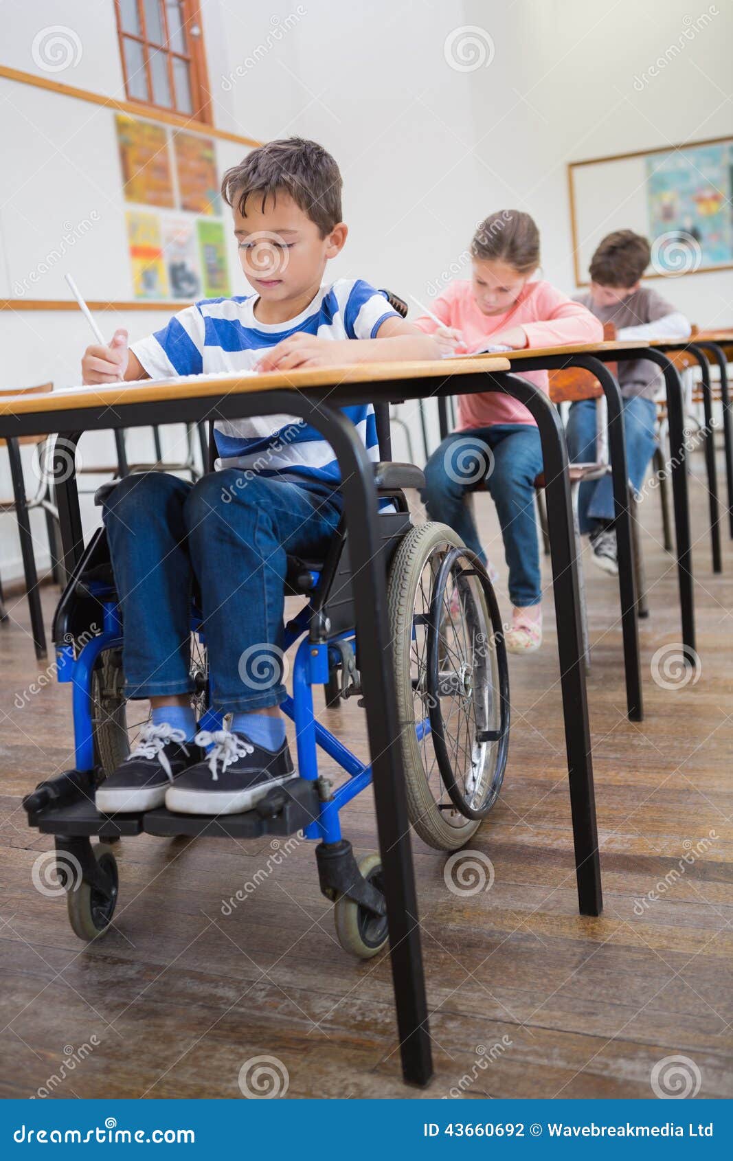 Disabled Pupil Writing at Desk in Classroom Stock Photo - Image of ...