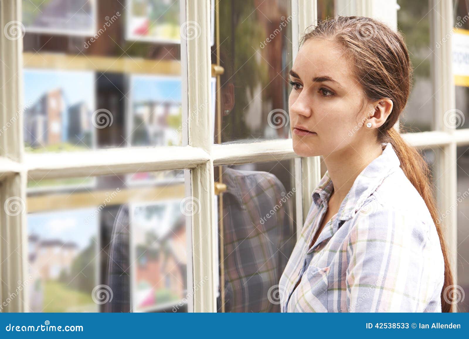Disappointed Young Woman Looking In Window Of Estate Agents Stock Image ...