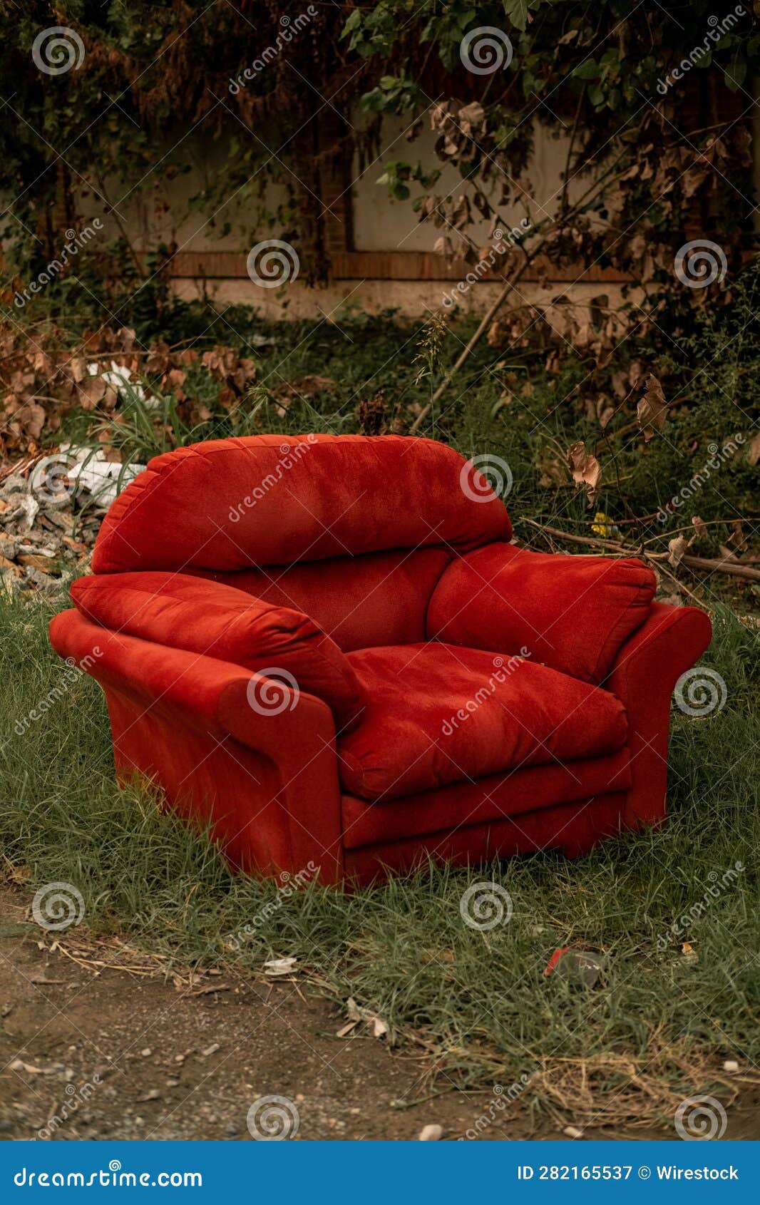 A Discarded Red Couch on Grass by a Brick Wall in a Field Stock Image ...