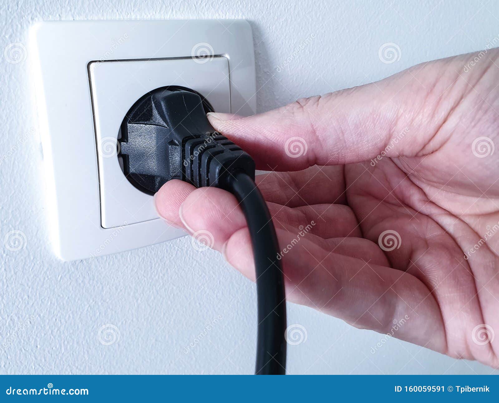 Disconnecting Black Electrical Power Plug with a Hand Inside a White ...