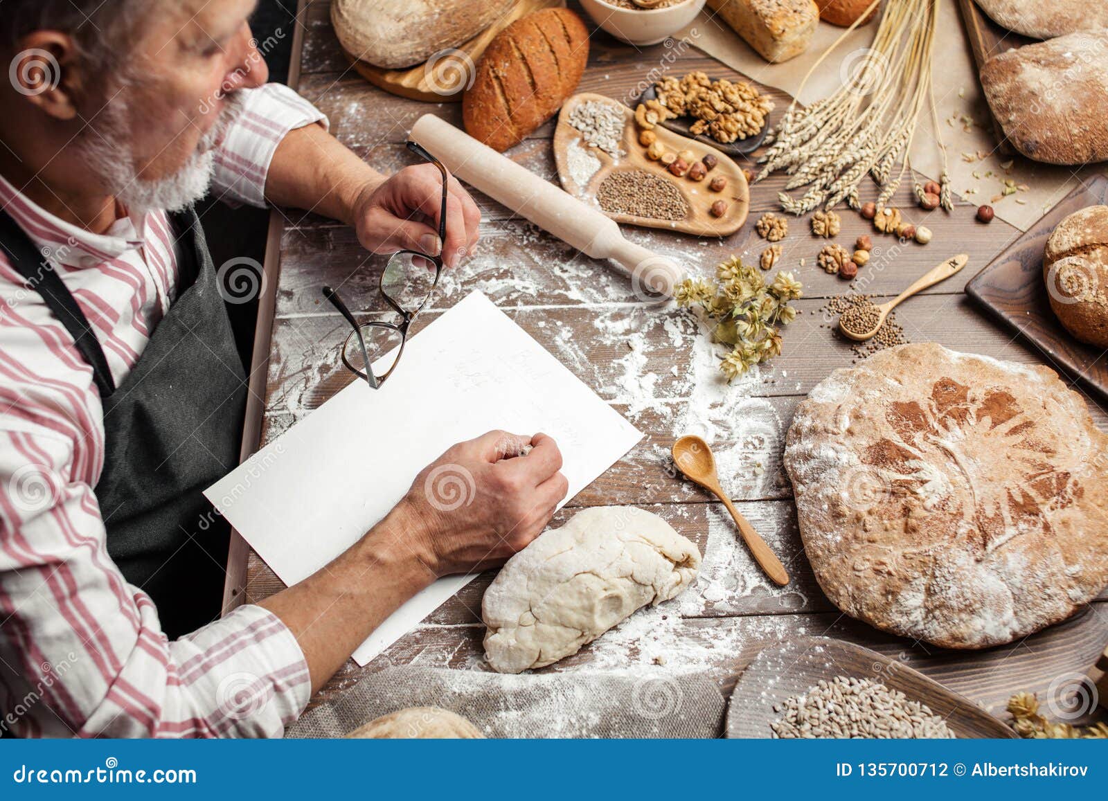 Old Baker Writing Down Old-time Recipe in Bakery Notebook Surrounded by ...