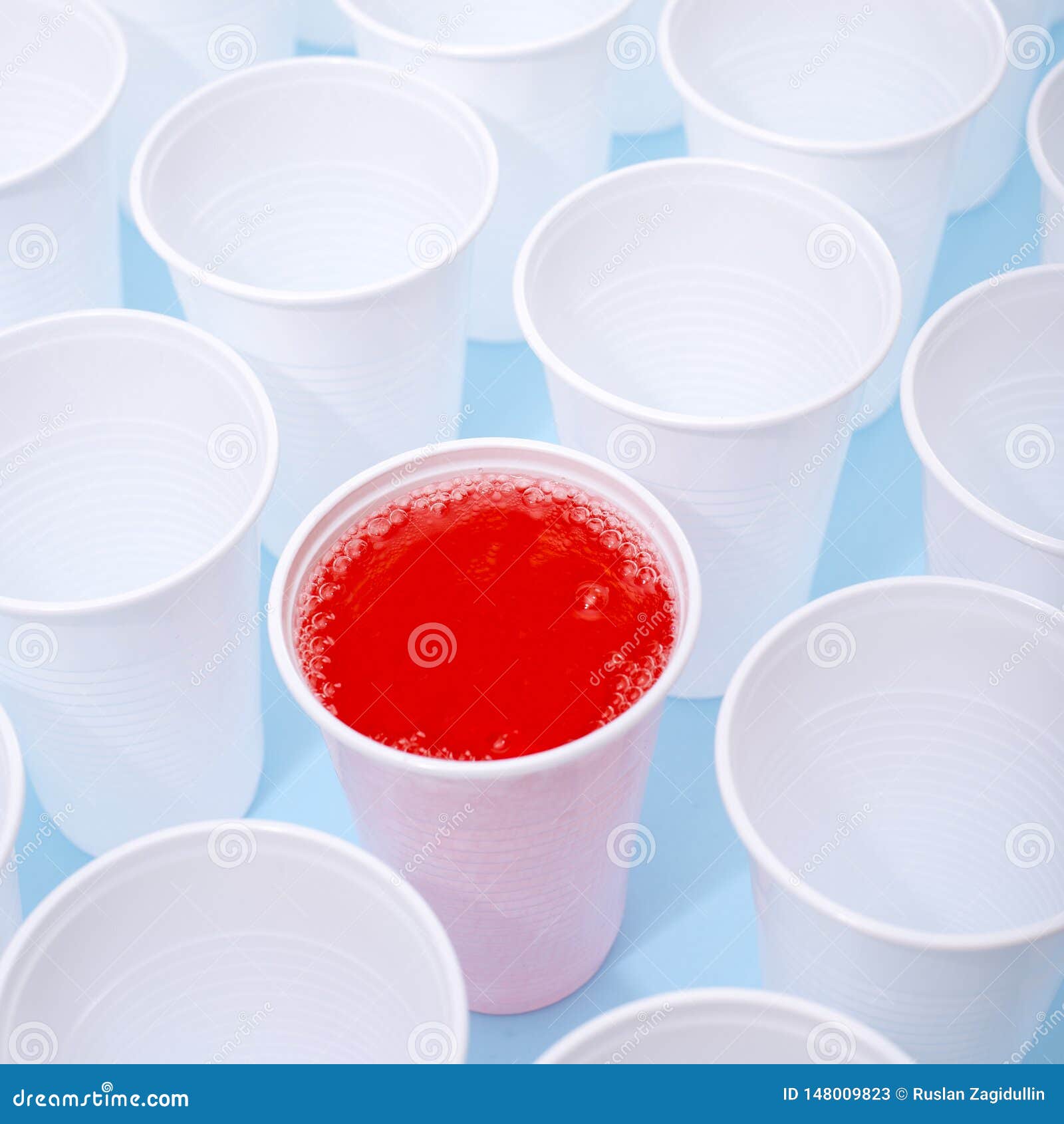Disposable Plastic White Empty Cups on and One Glass Filled with Red ...