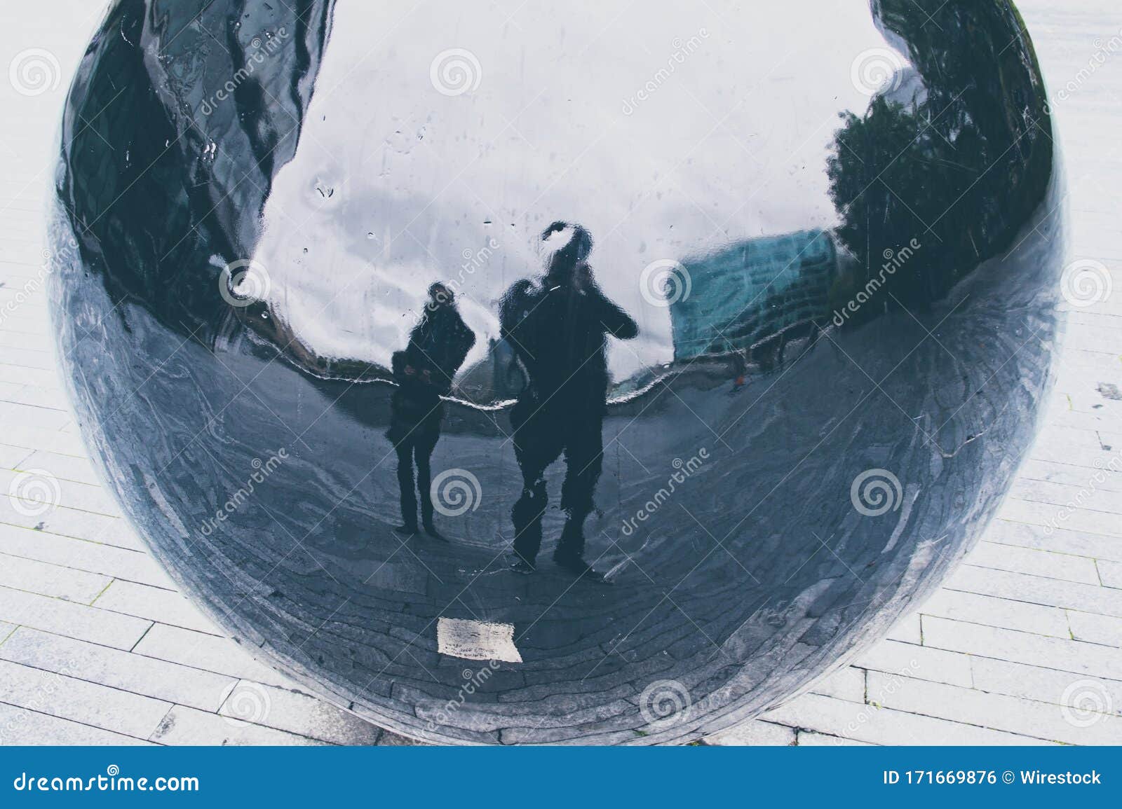A Distorted Reflection of Two People Being Created by a Spherical Ball ...