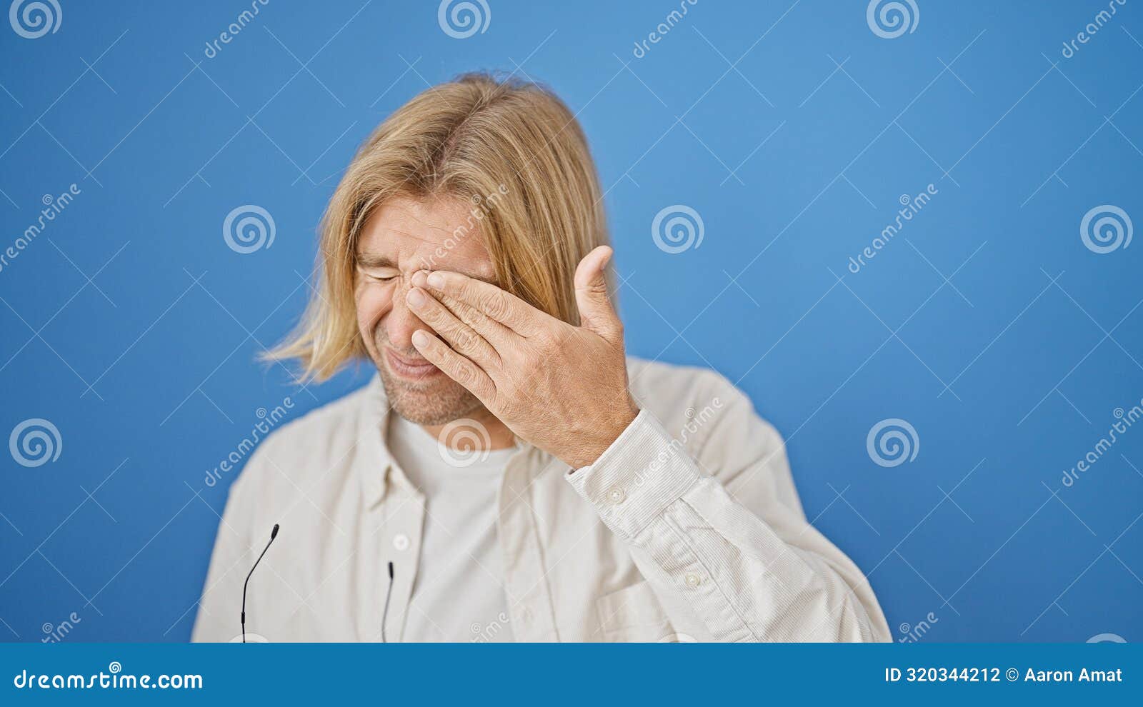 A Distressed Man Facepalming Against a Blue Background, Embodying ...