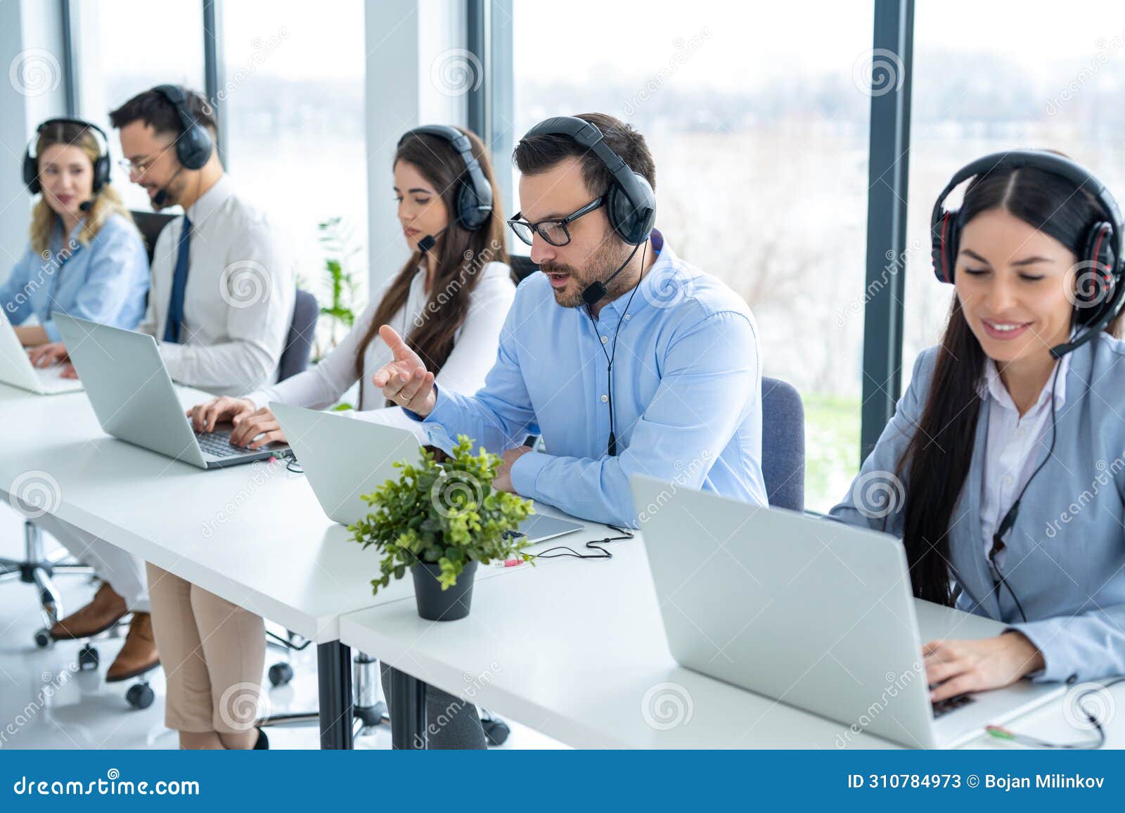 Diverse Call Center Workers Sitting in Row and Communicating with ...