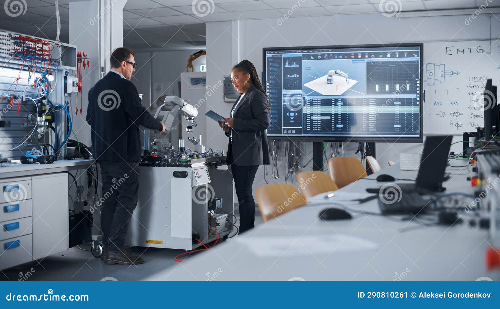 Diverse Colleagues Standing Near Table with Robot Arm and Discussing ...