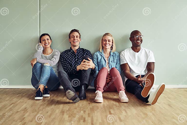 Diverse Coworkers Sitting And Laughing Together On An Office Flo Stock