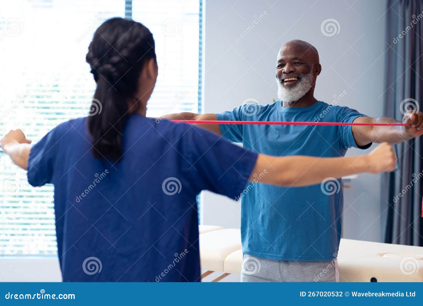 Diverse Female Physiotherapist Helping Smiling Senior Male Patient
