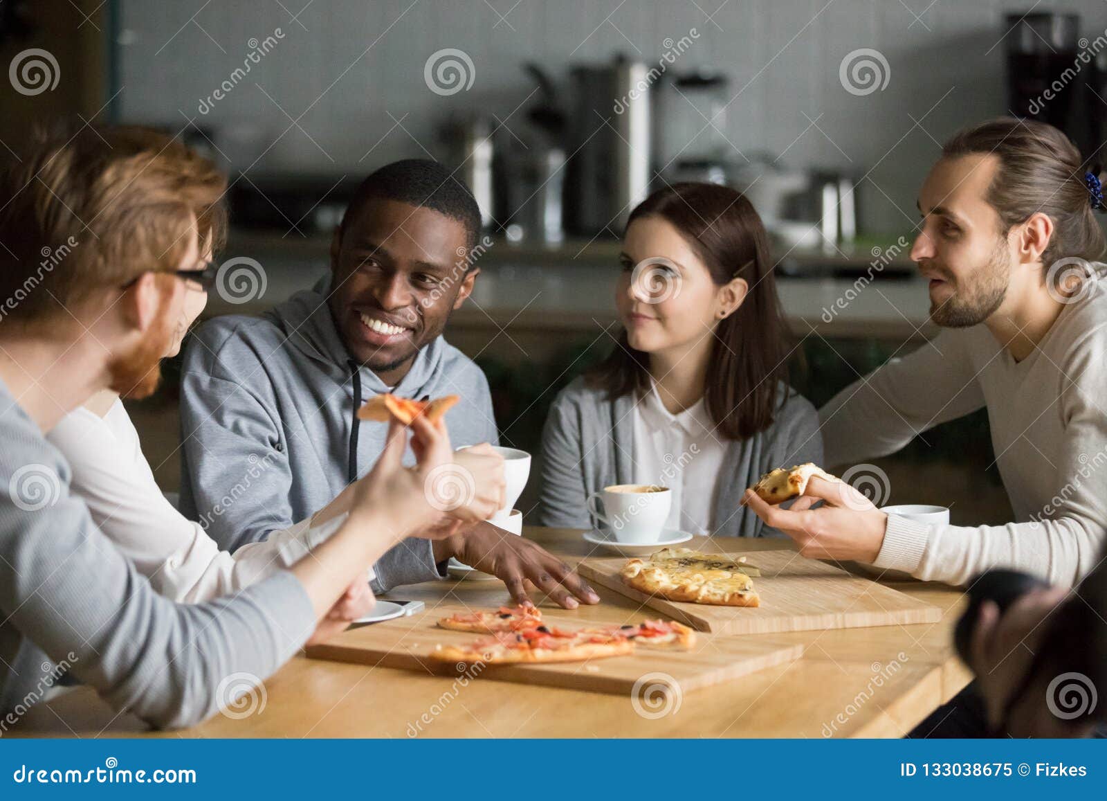 Diverse Friends Eat Pizza Enjoying Interesting Talk At Table Stock