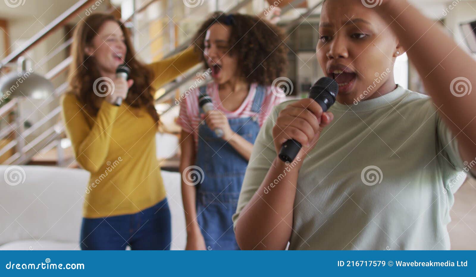Diverse Group Of Female Friends Having Fun Singing Karaoke At Home