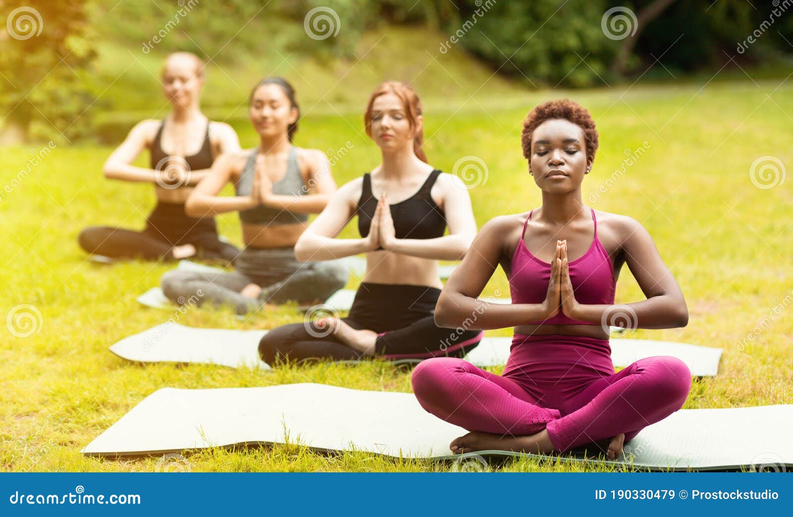 Diverse Millennial Women Meditating In Lotus Pose And Doing Namaste