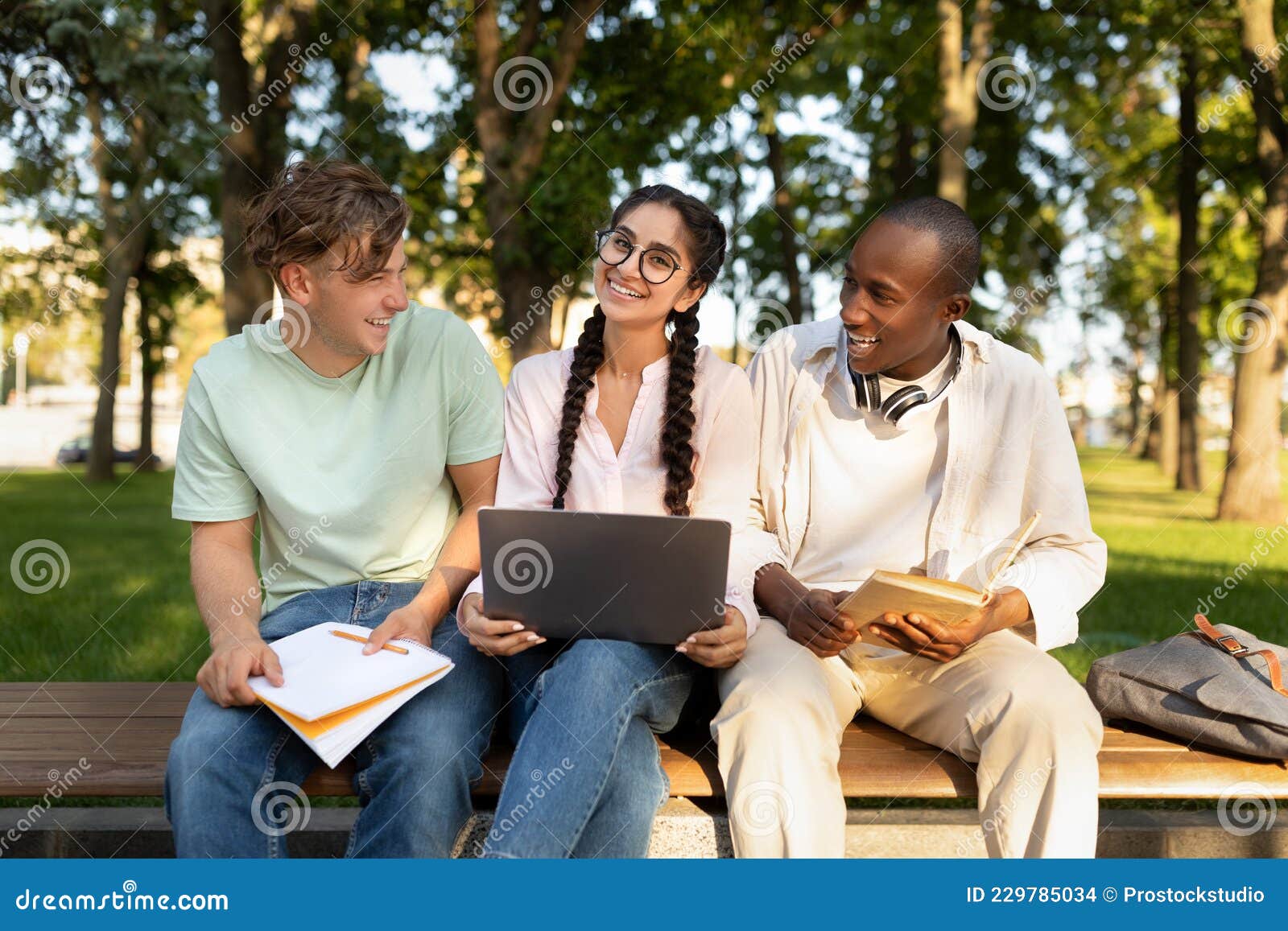 Diverse Students Friends Learning Sitting on Bench, Using Laptop ...