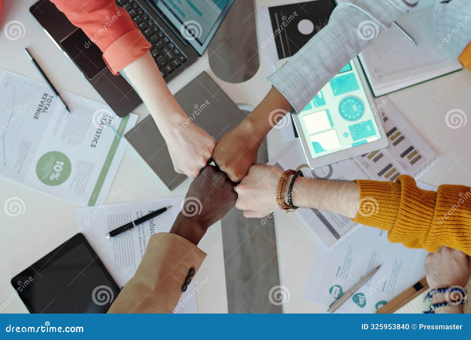 Diverse Team Members Fist Bumping Over Desk in Office Stock Photo ...