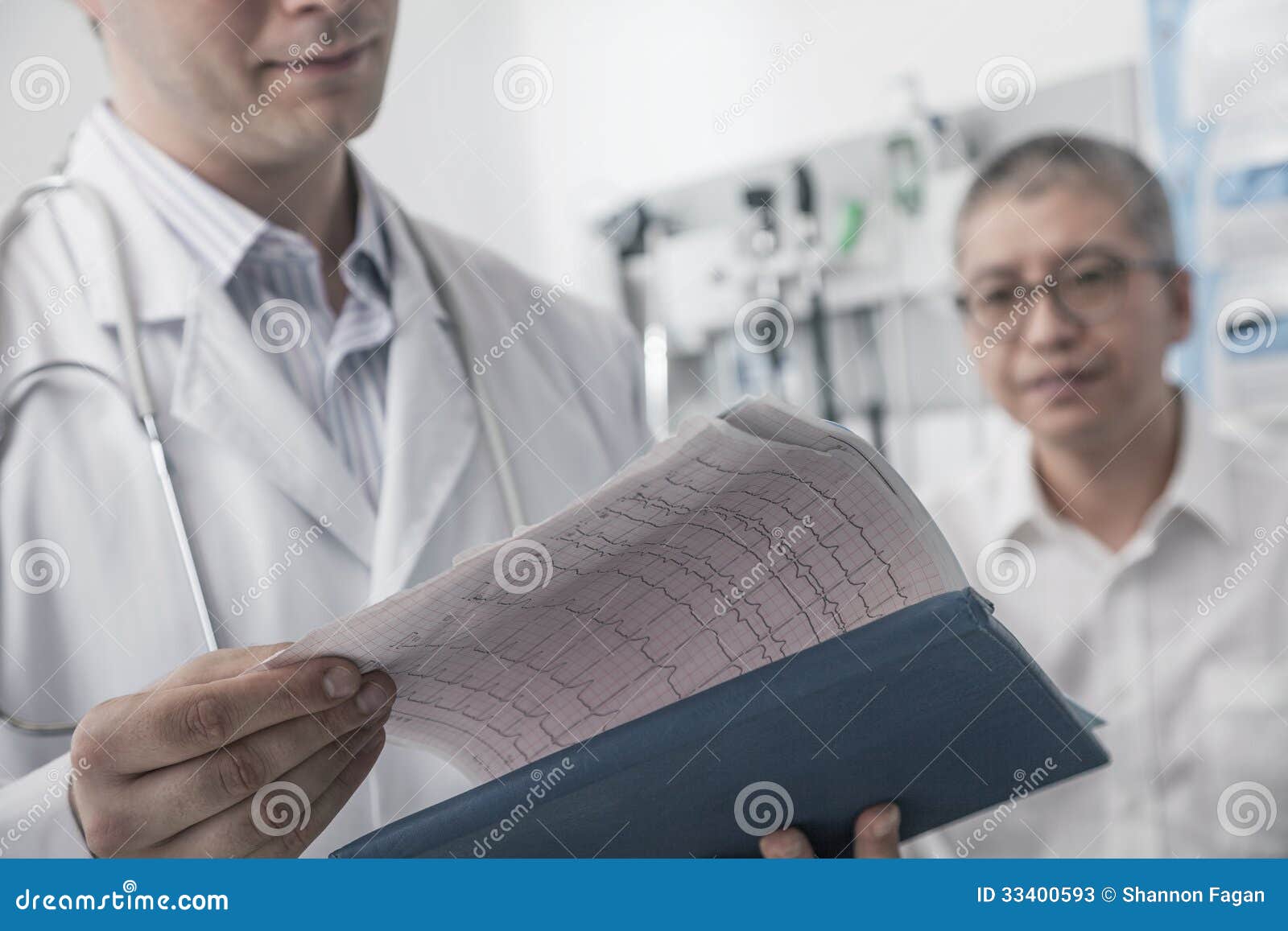 Doctor Checking Medical Chart with Patient in the Background Stock ...