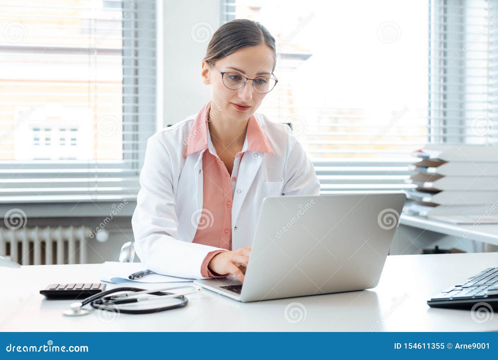 Doctor Doing Paperwork on Computer Sitting on Desk Stock Image - Image ...