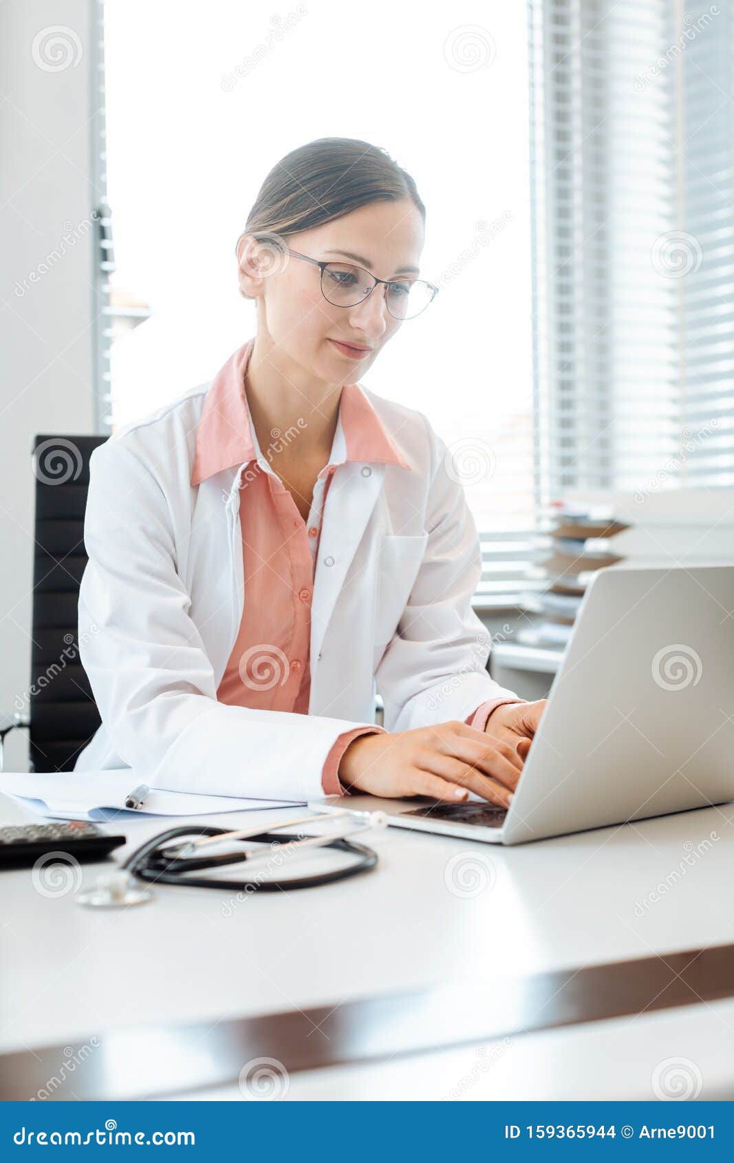 Doctor Doing Paperwork on Computer Sitting on Desk Stock Photo - Image ...